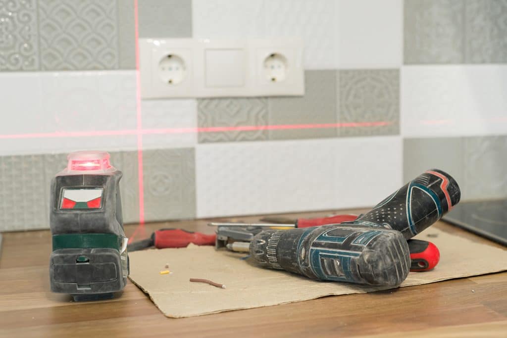 Electrician using infrared laser level to install electrical outlets ...